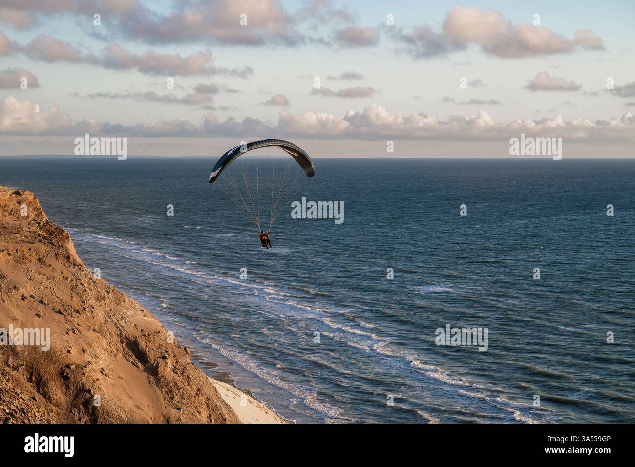 Paraglider soaring above North sea near rugged coastal cliff, Denmark ...