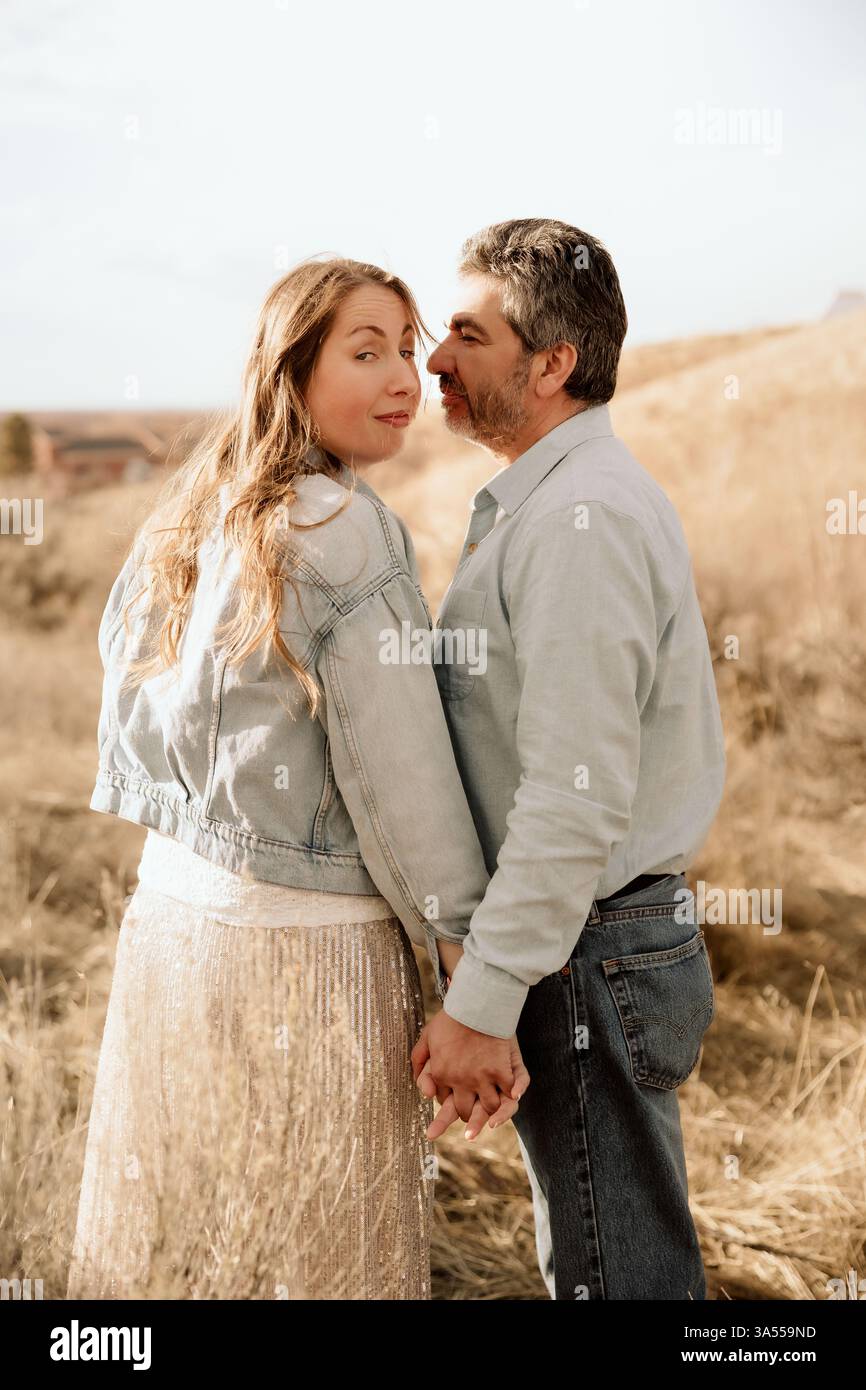 A couple holds hands, playfully looking back together Stock Photo - Alamy