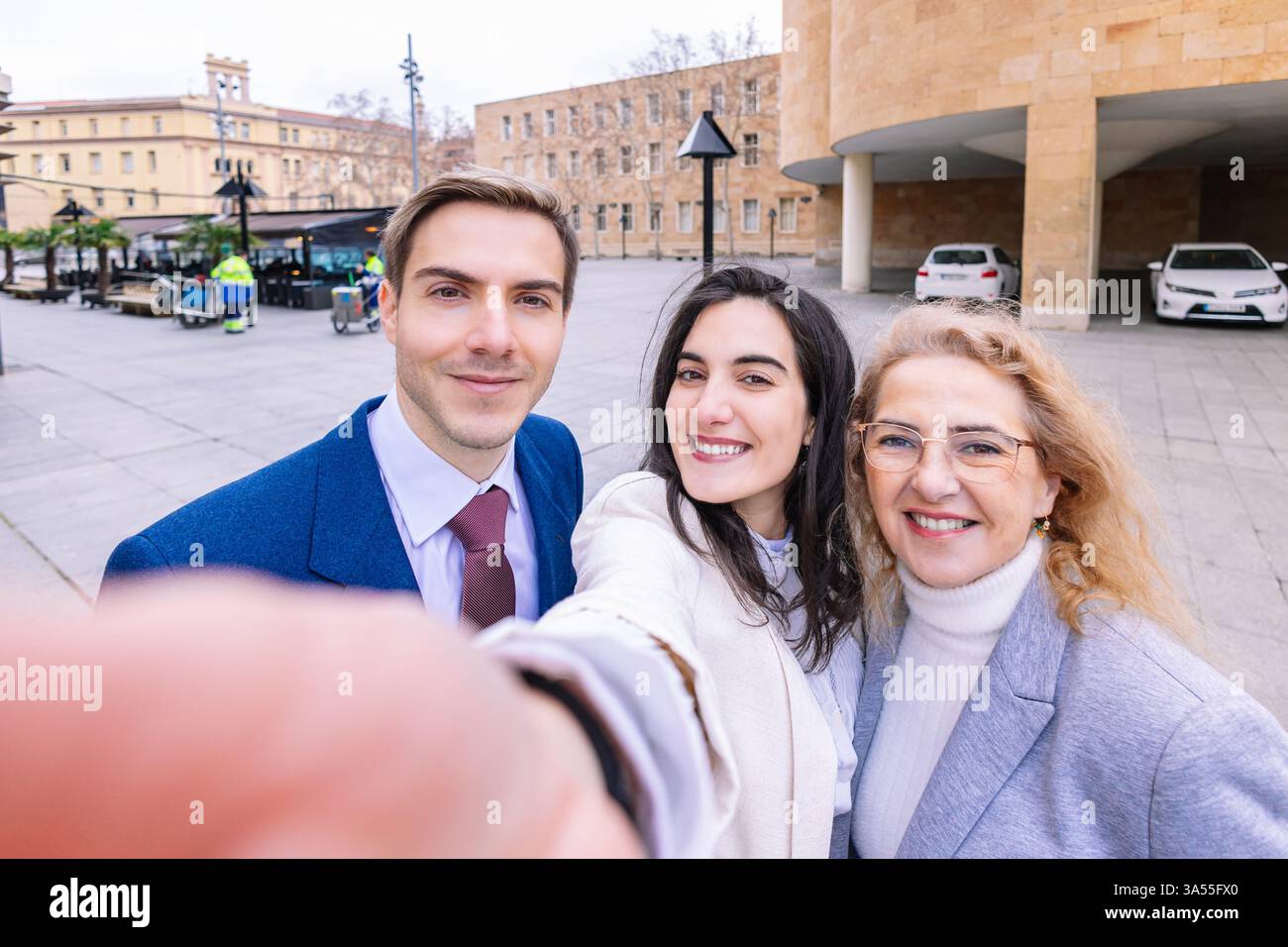 Three smiling business professionals taking a selfie in an urban ...