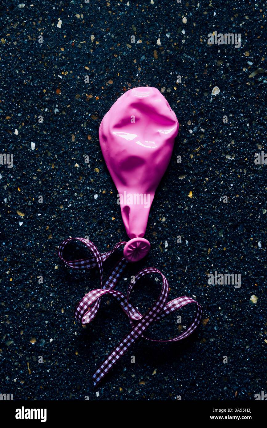 Deflated pink balloon on a wet road Stock Photo - Alamy