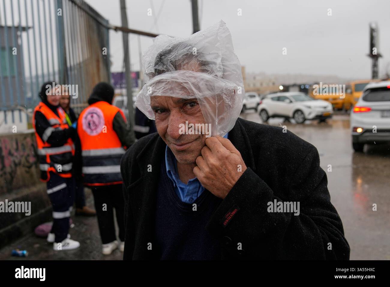 A Palestinian man braves the rain while he tries to cross from the ...