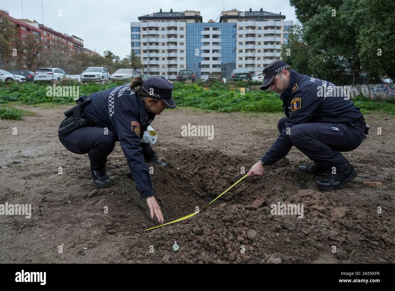 Two police officers look at the hole left by a pyrotechnic device on ...