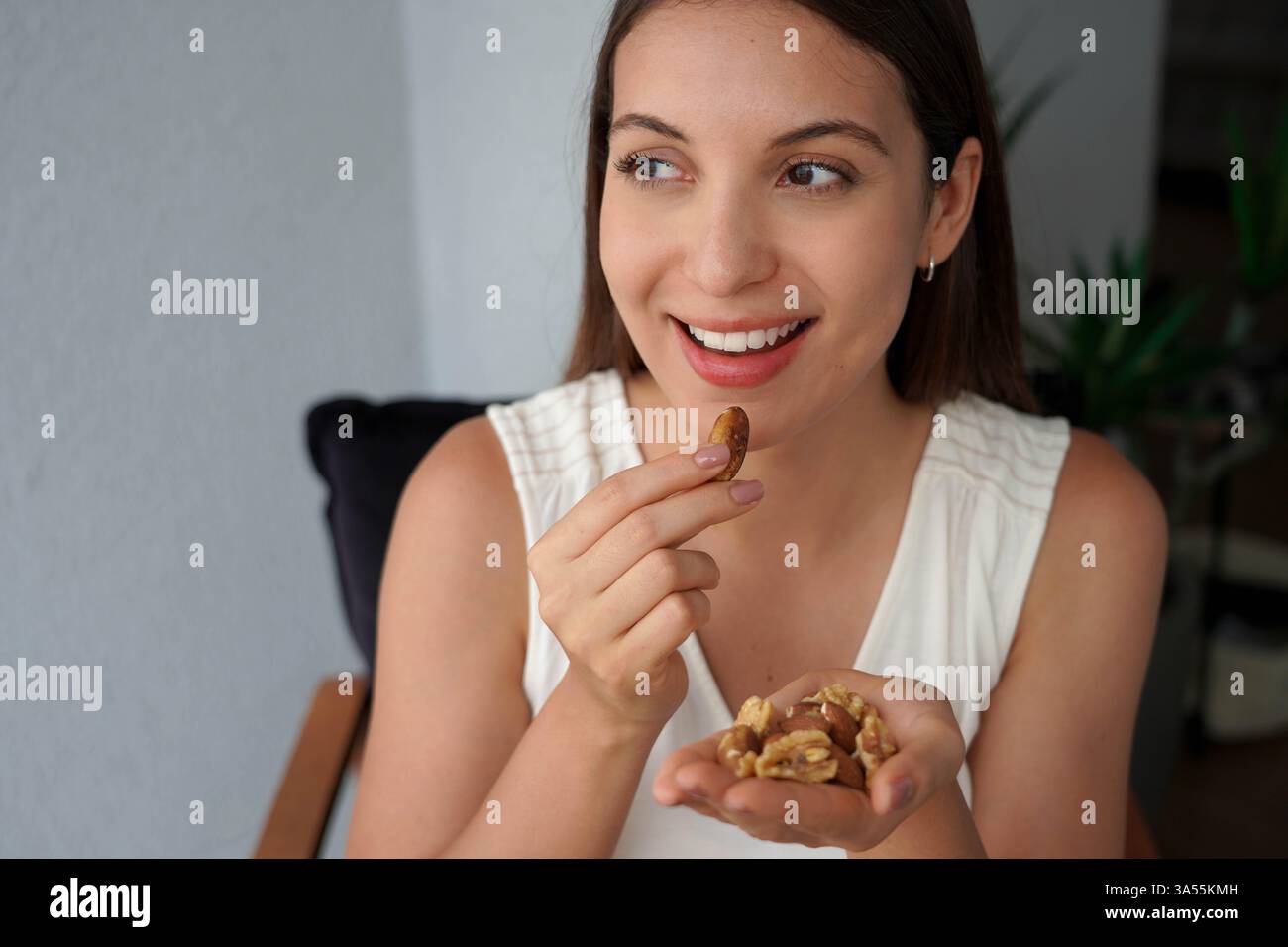 Beautiful girl eating a nut from her hand Stock Photo - Alamy