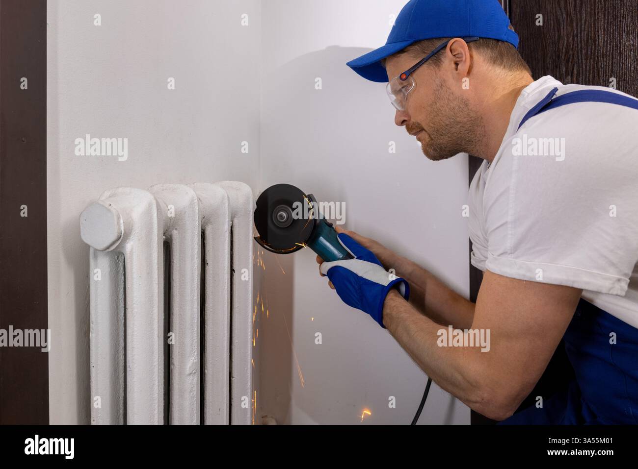 worker cuts off old cast iron radiator with angle grinder. house ...