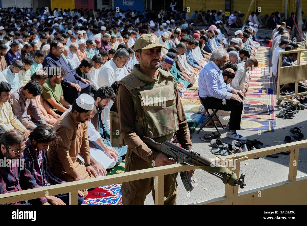 A police officer stands guard as Muslims offer third Friday prayer ...