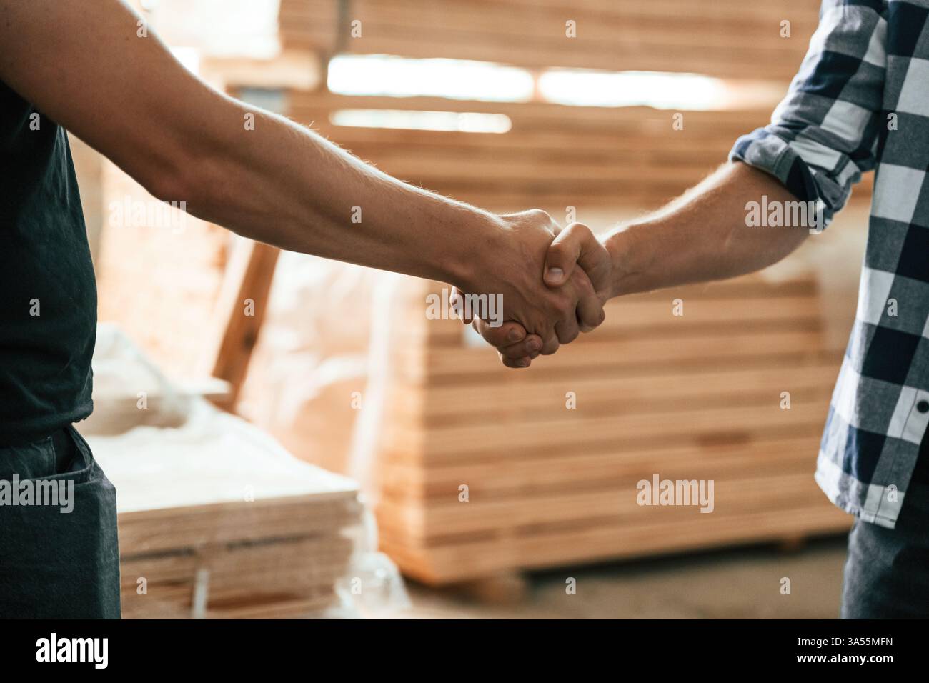 Close up view, doing handshake. Two workers are in the industrial ...