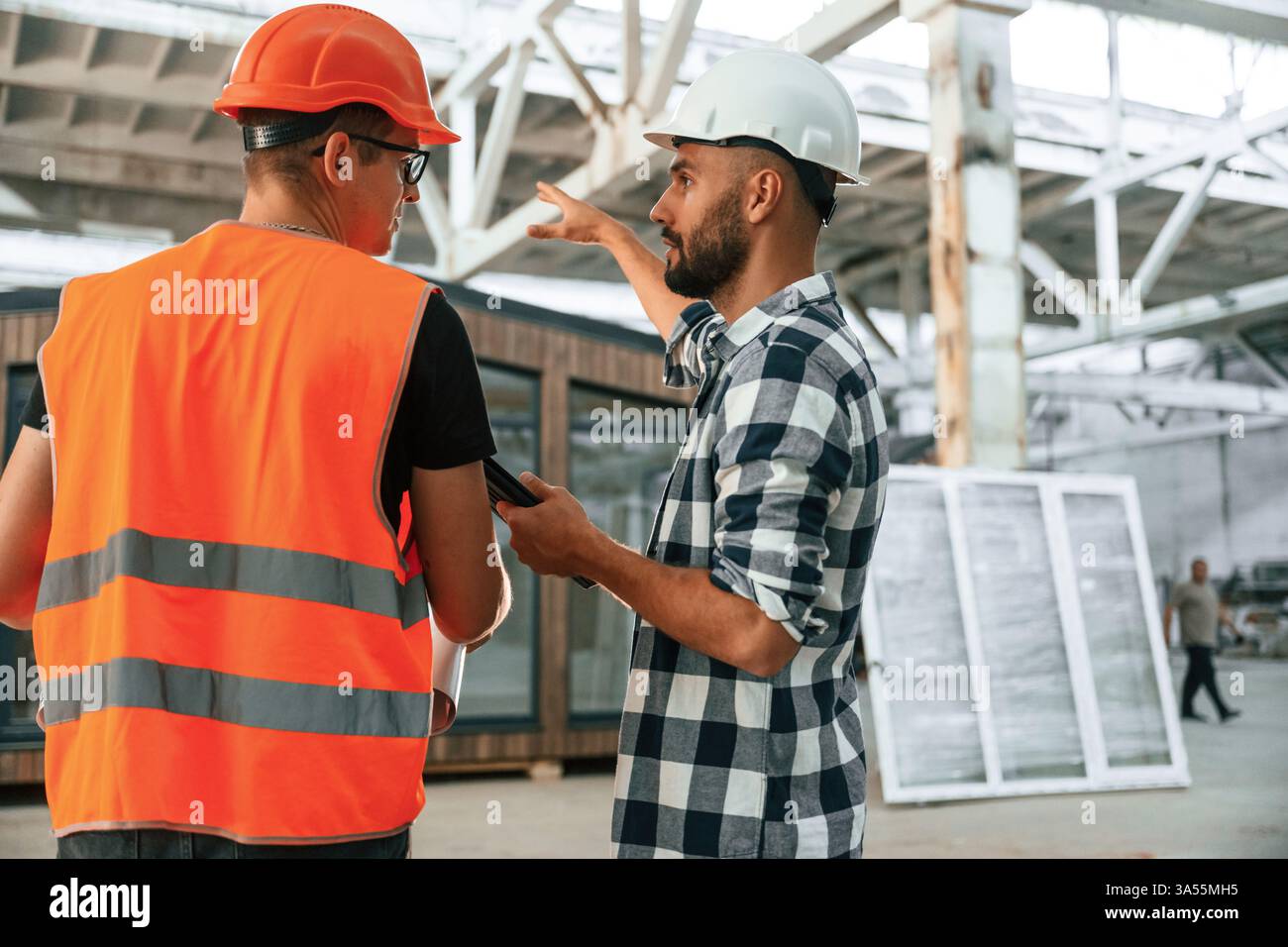 Builder is talking with manager or architect. Two workers are in the ...