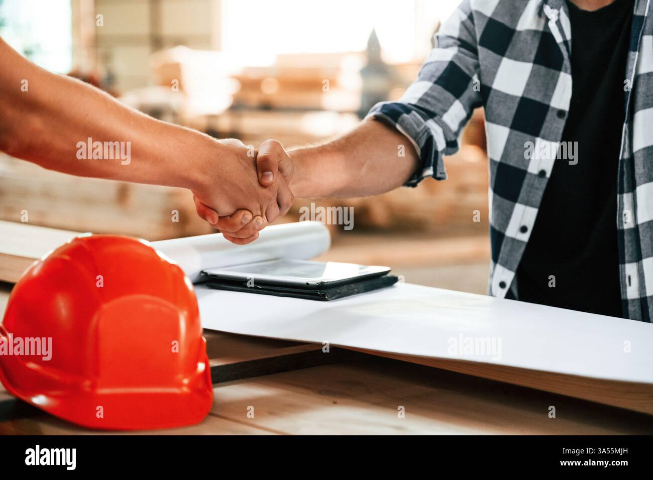 Having a deal, handshake. Two workers are in the industrial wooden ...