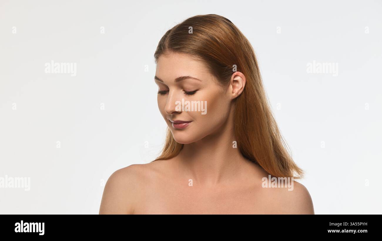 Attractive young woman with perfect skin tilting head slightly downward ...