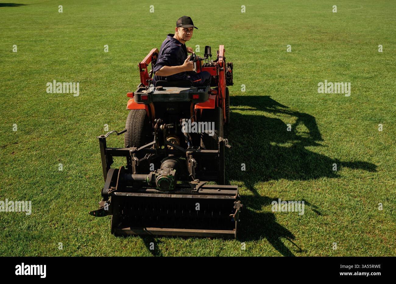 Driving, looks behind, shows thumb up. Man is with utility tractor with ...