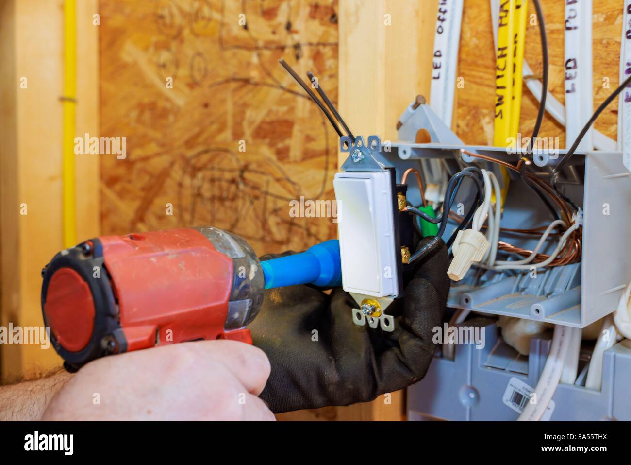 An electrician is connecting wires to switch inside wall panel box in ...