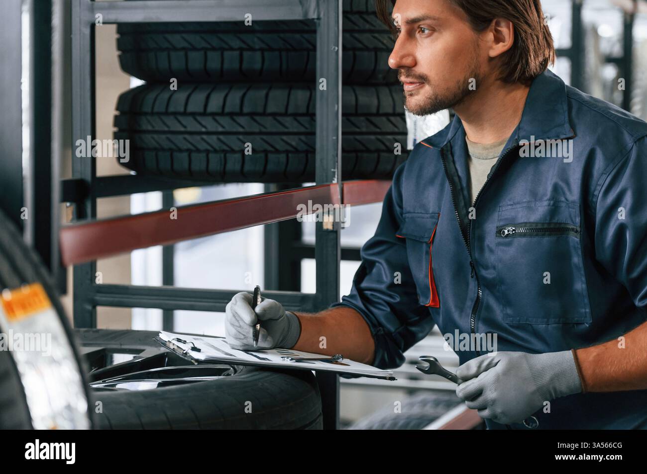 Writing the data into notepad. Man is in the tire fitting car service ...