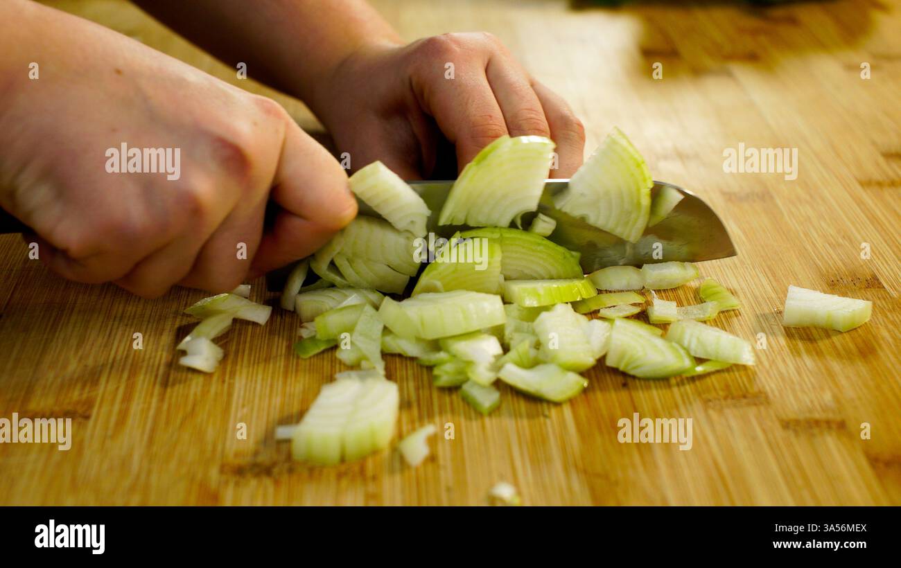 An onion gets chopped, sliced and diced on a wooden counter top in a ...
