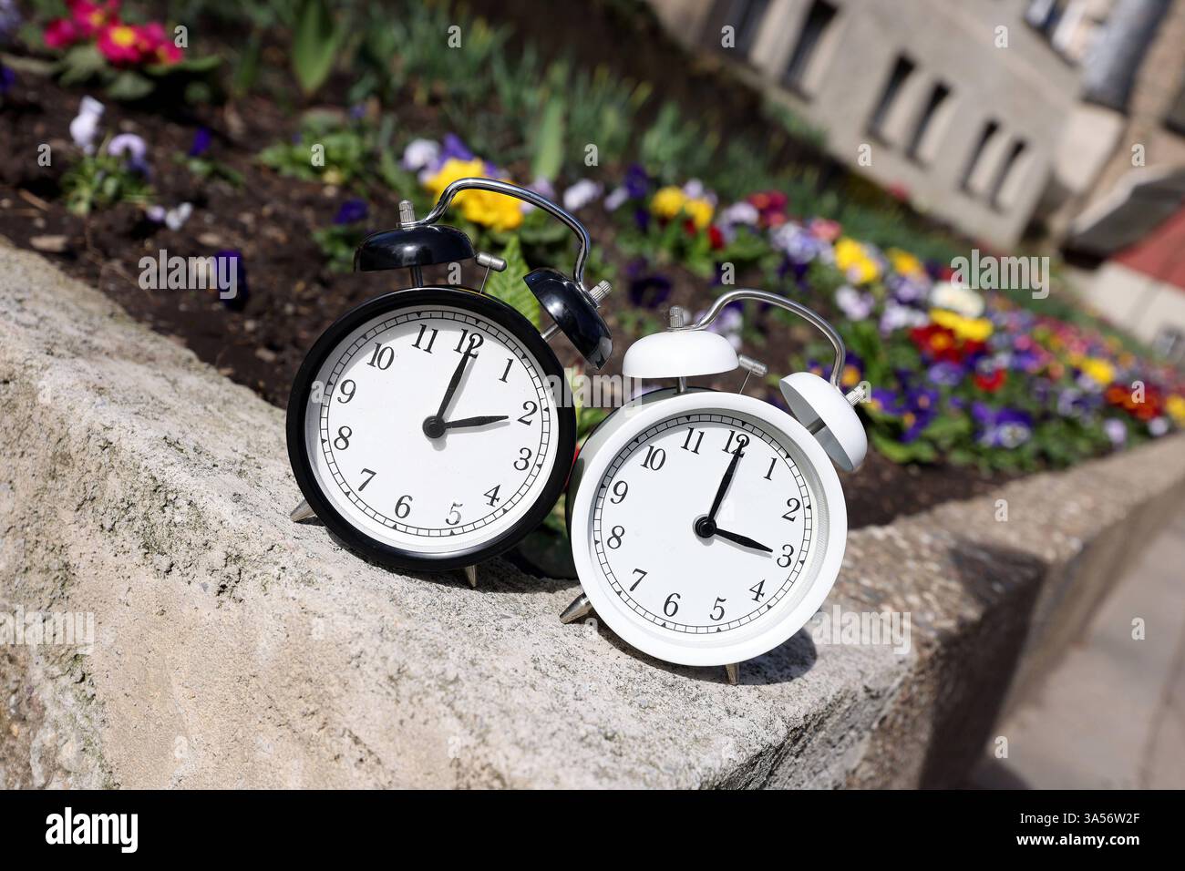 Ein Wecker zeigt zwei Uhr und der andere drei Uhr. Die Uhren werden am ...
