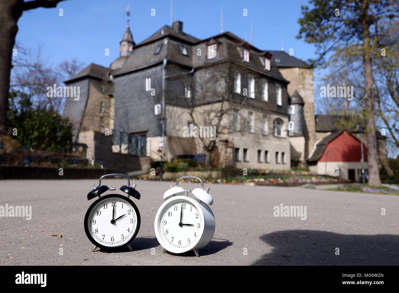 Ein Wecker zeigt zwei Uhr und der andere drei Uhr. Die Uhren werden am ...