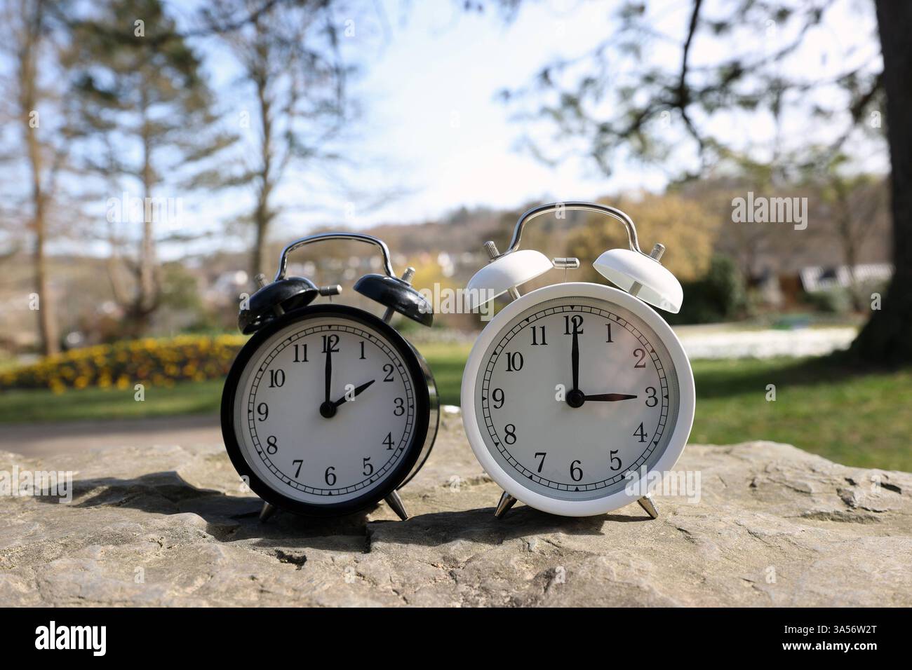 Ein Wecker zeigt zwei Uhr und der andere drei Uhr. Die Uhren werden am ...