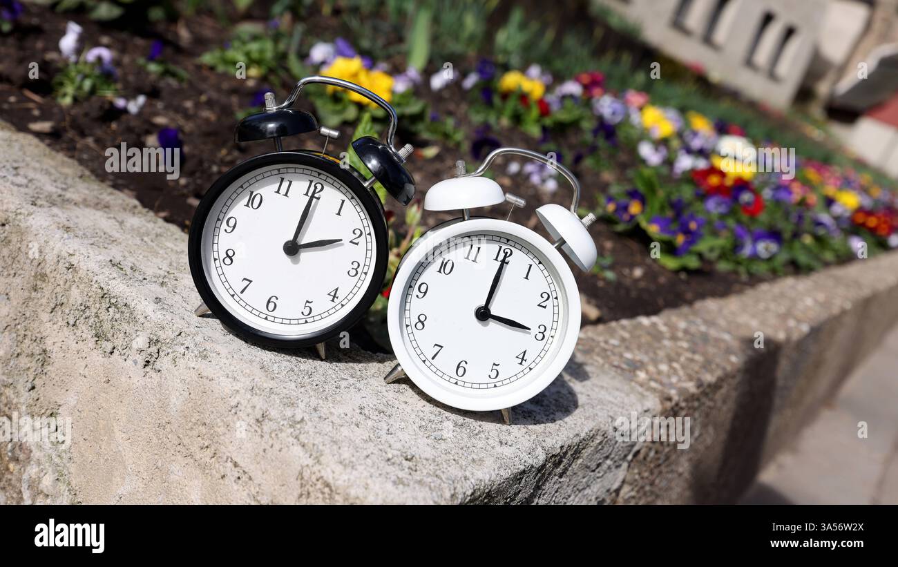Ein Wecker zeigt zwei Uhr und der andere drei Uhr. Die Uhren werden am ...