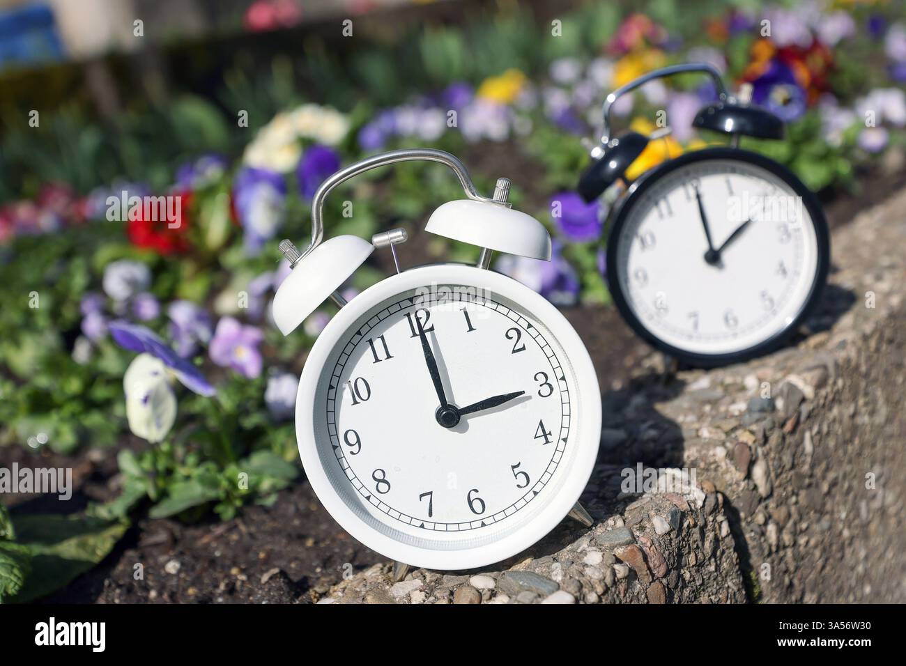 Ein Wecker zeigt zwei Uhr und der andere drei Uhr. Die Uhren werden am ...