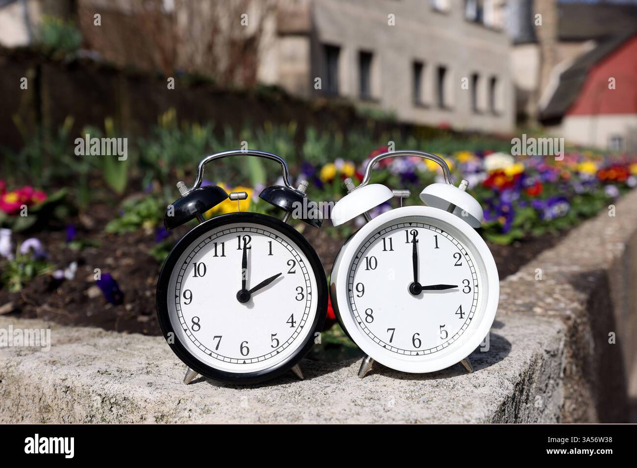 Ein Wecker zeigt zwei Uhr und der andere drei Uhr. Die Uhren werden am ...