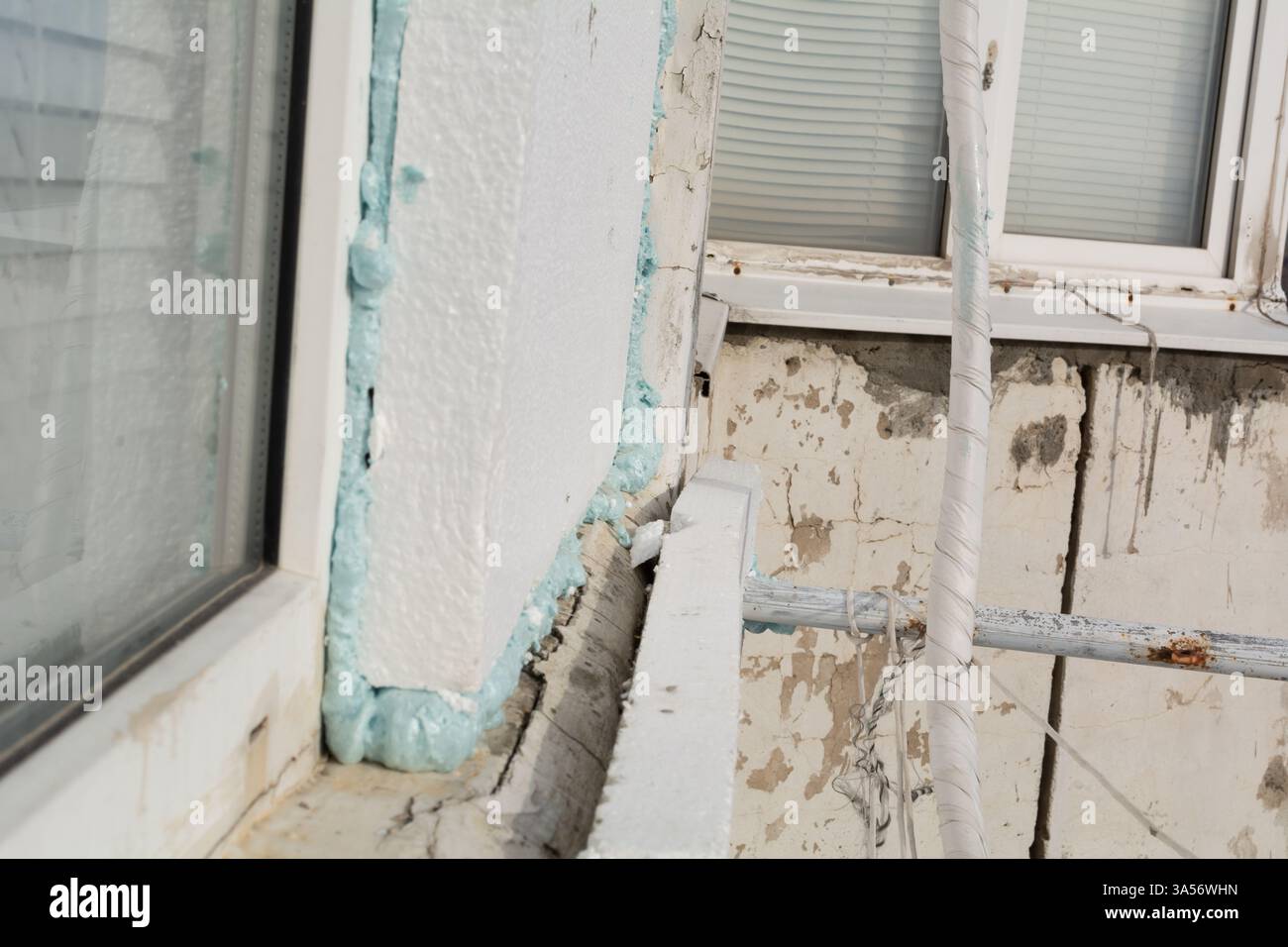 Fastening polystyrene foam to the building facade with blue mounting foam. Insulation of the ...