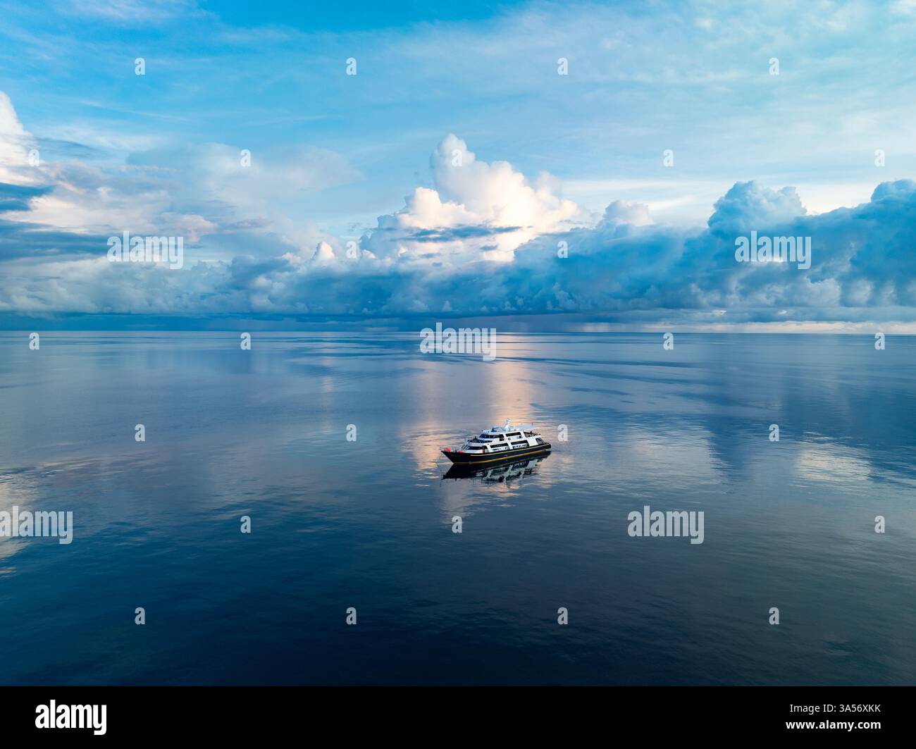 A sunrise illuminates the calm seas surrounding the Togian Island of ...