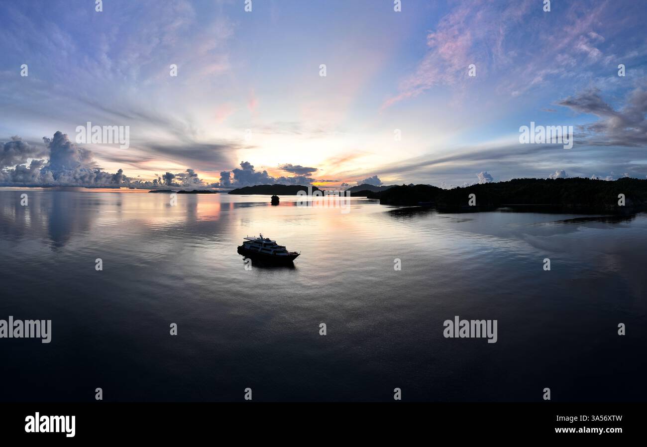 A sunrise illuminates the calm seas surrounding the Togian Island of ...
