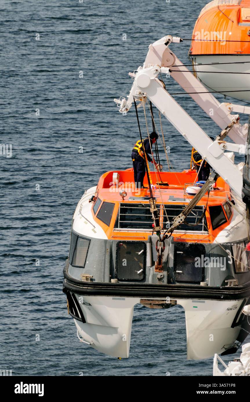 A lifeboat (tender) of a cruise ship being serviced by the crew while ...