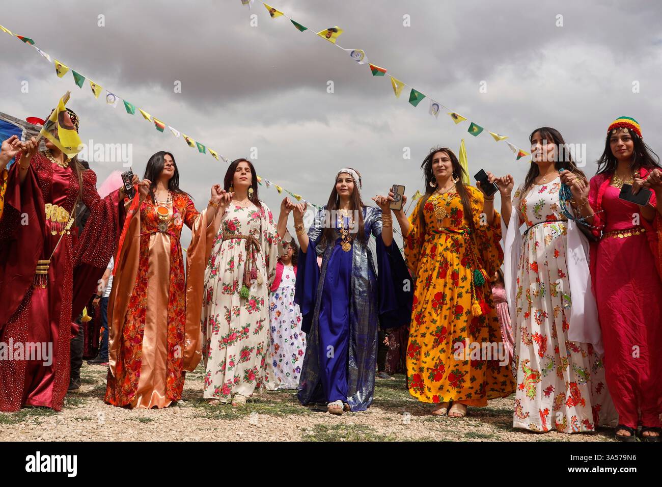 Syrian Kurdish women, wearing traditional clothing, dance as they ...
