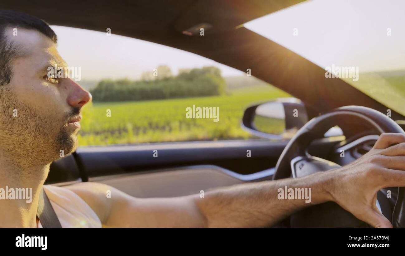 Profile of young handsome man driving a modern electric car with ...