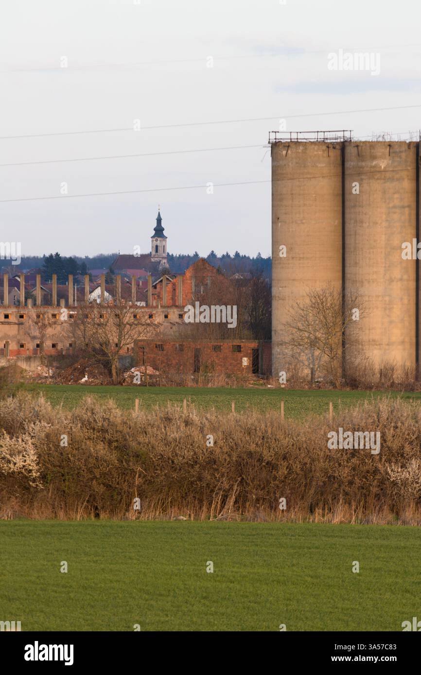 A serene countryside scene includes silos, abandoned buildings, a ...