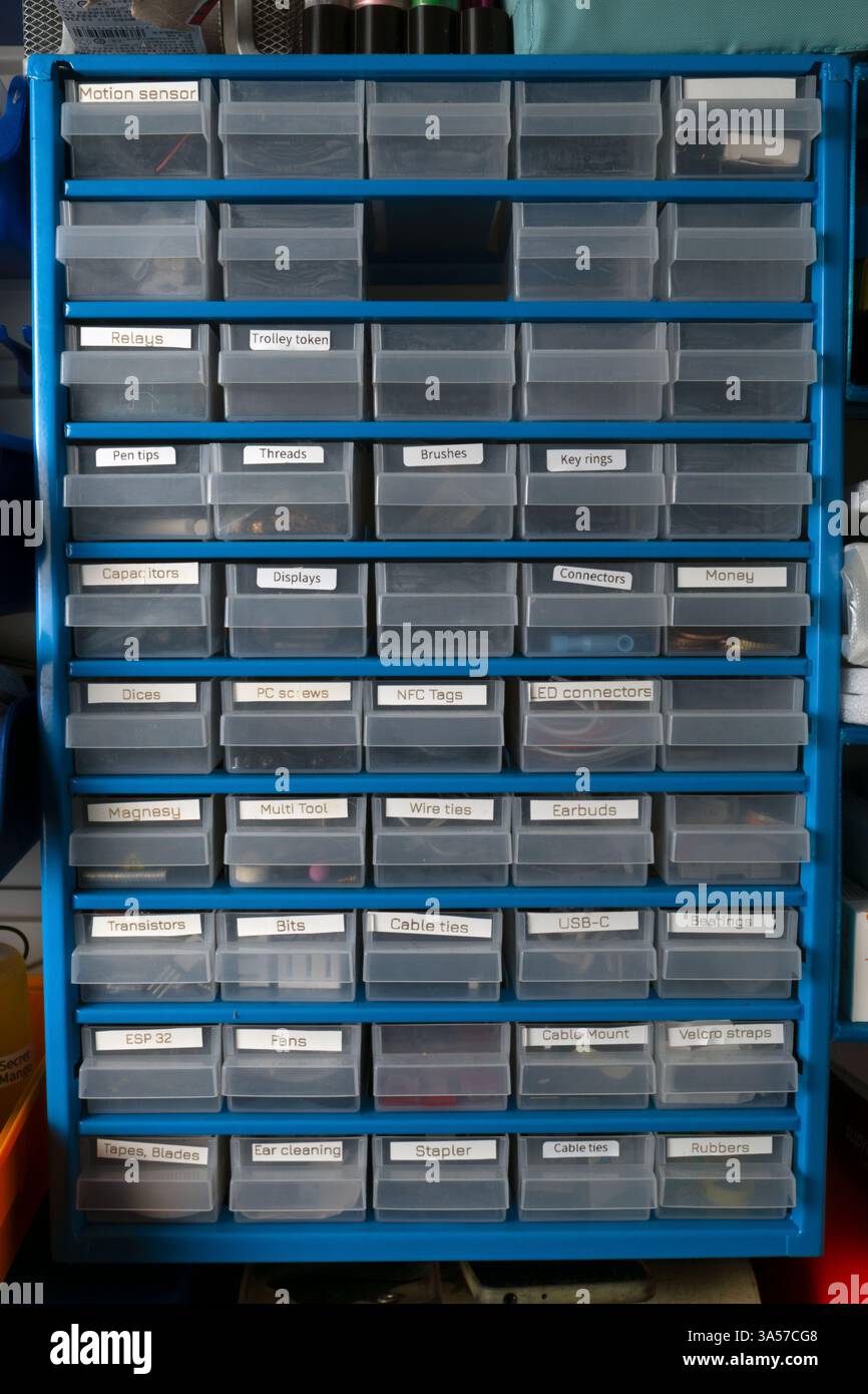 A blue storage unit with many compartments and labels. The compartments ...