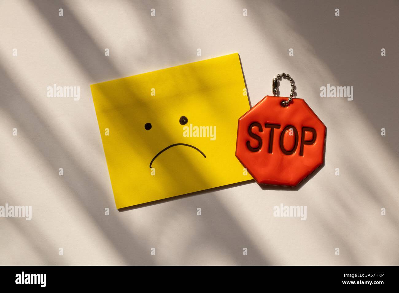 Yellow paper with sadness drawn on it and reflective sign with stop ...