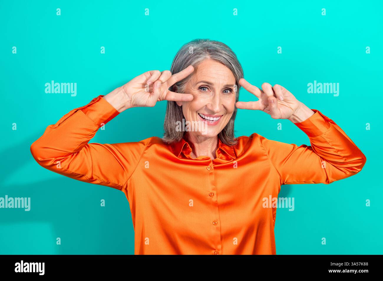 Portrait of a mature woman making peace sign gestures, smiling joyfully ...