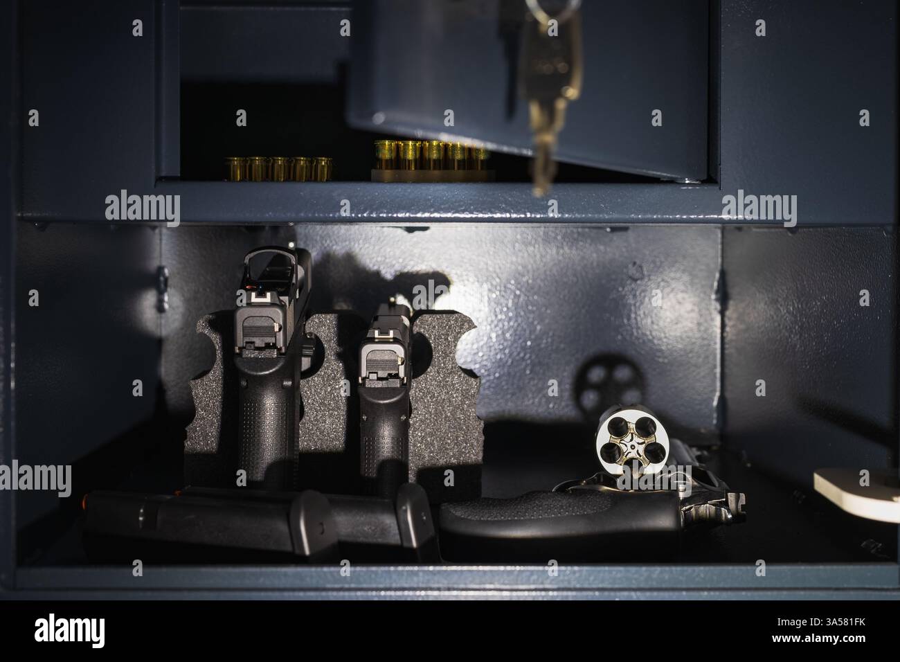 Pistols, a revolver and ammunition in a gun safe illuminated by a ...