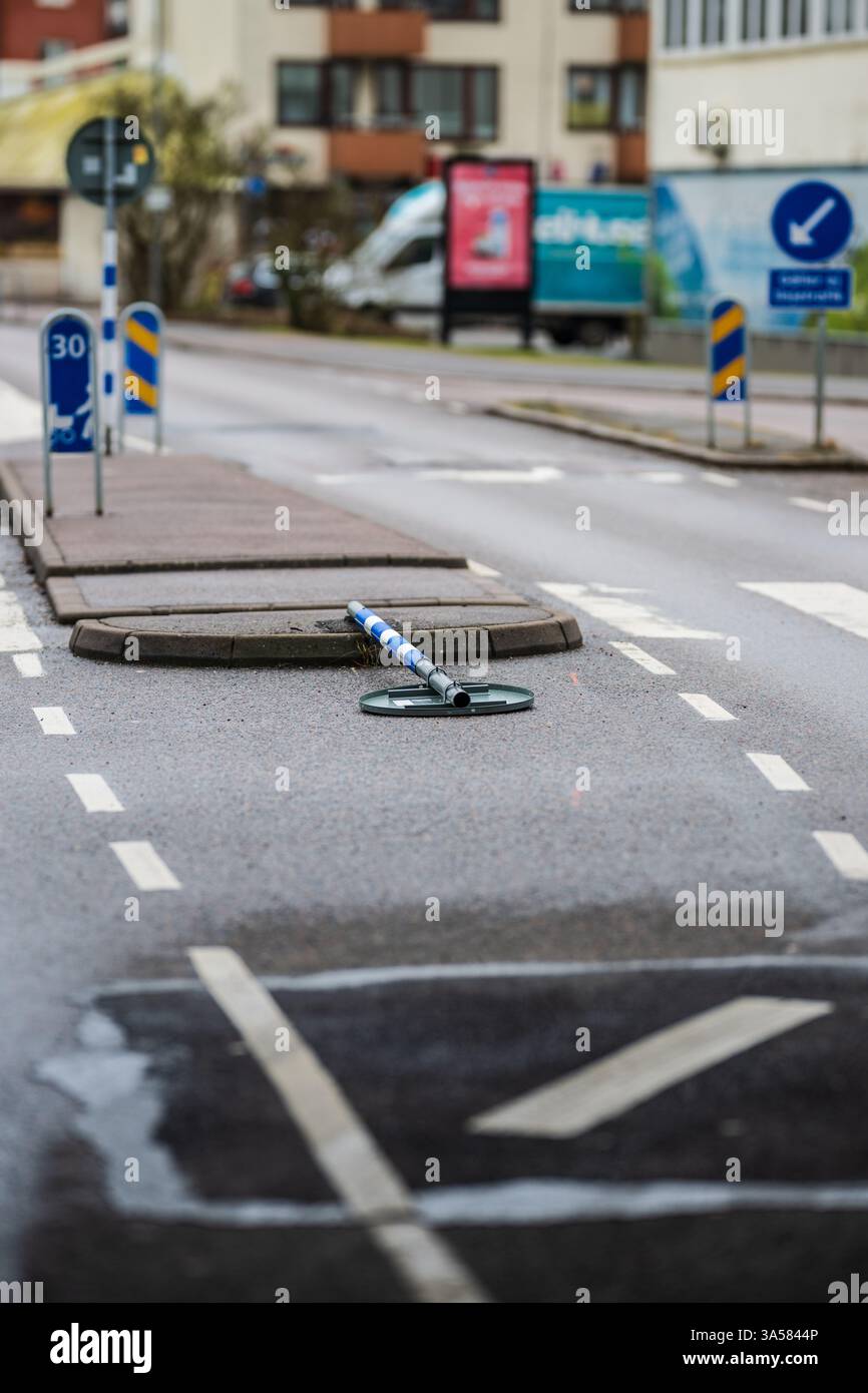 road with white lane markings and fallen blue and white striped pole ...