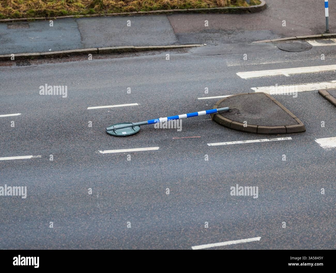 road with white lane markings and fallen blue and white striped pole ...