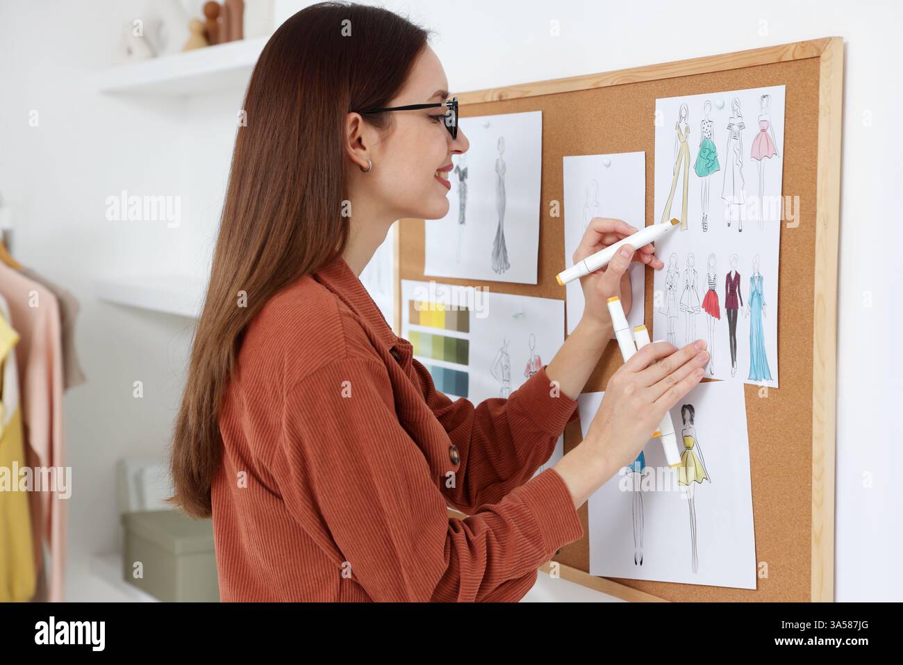 Fashion designer drawing sketch of clothes in workshop Stock Photo - Alamy