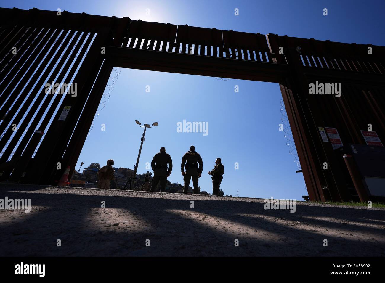Border Patrol agents and members of the military stand inside a gate in ...