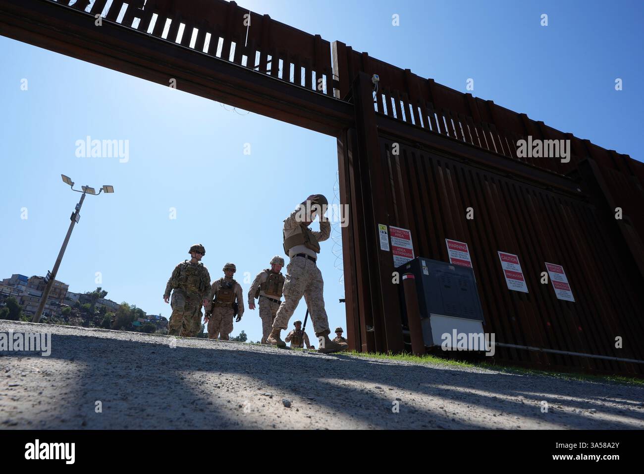 Border Patrol agents and members of the military walk between two ...