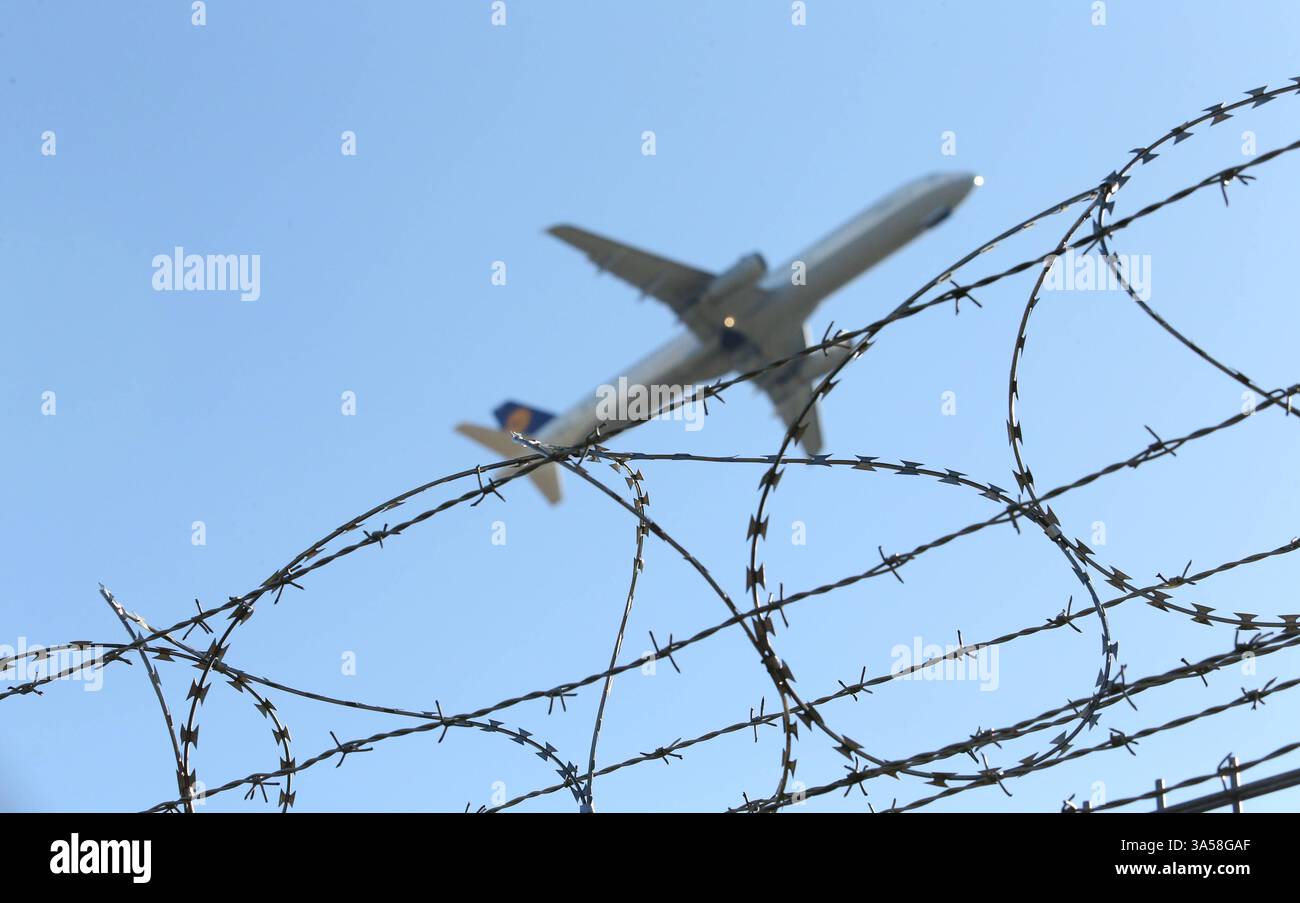 Ein Flugzeug hebt vom Flughafen Hamburg ab. Davor ist NATO-Draht zu ...