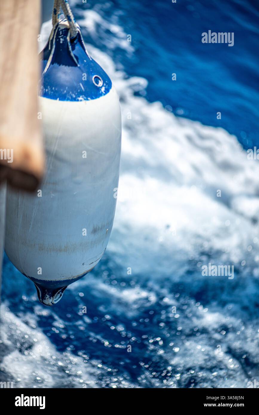 A detailed close-up of a fender secured to a sailboat, gently touching ...