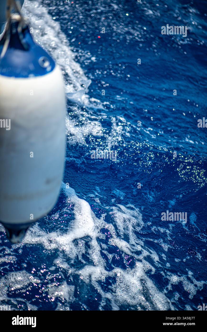 A detailed close-up of a fender secured to a sailboat, gently touching ...