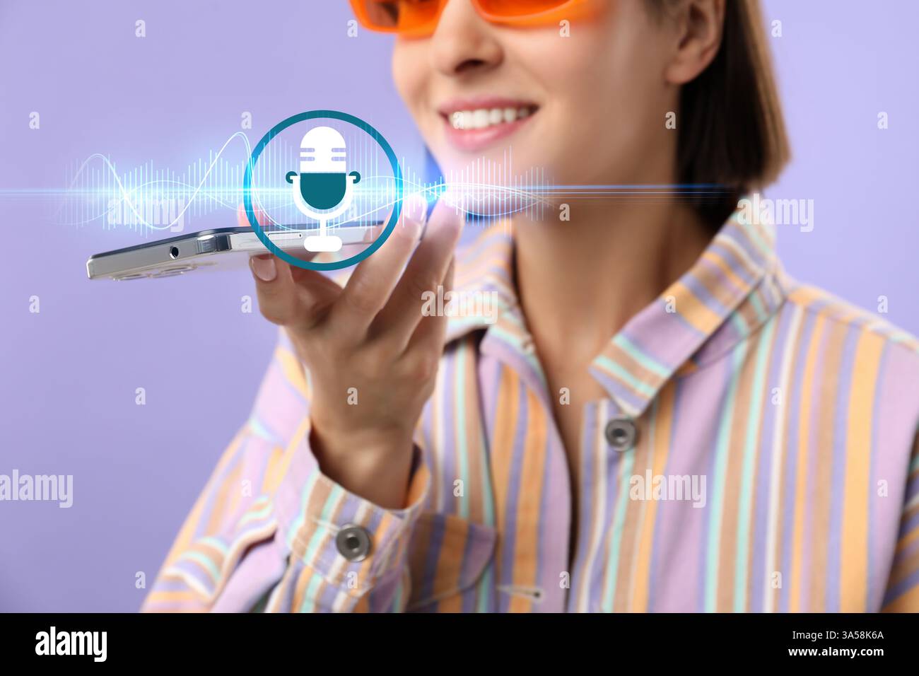 Young woman recording voice message via smartphone on violet background ...