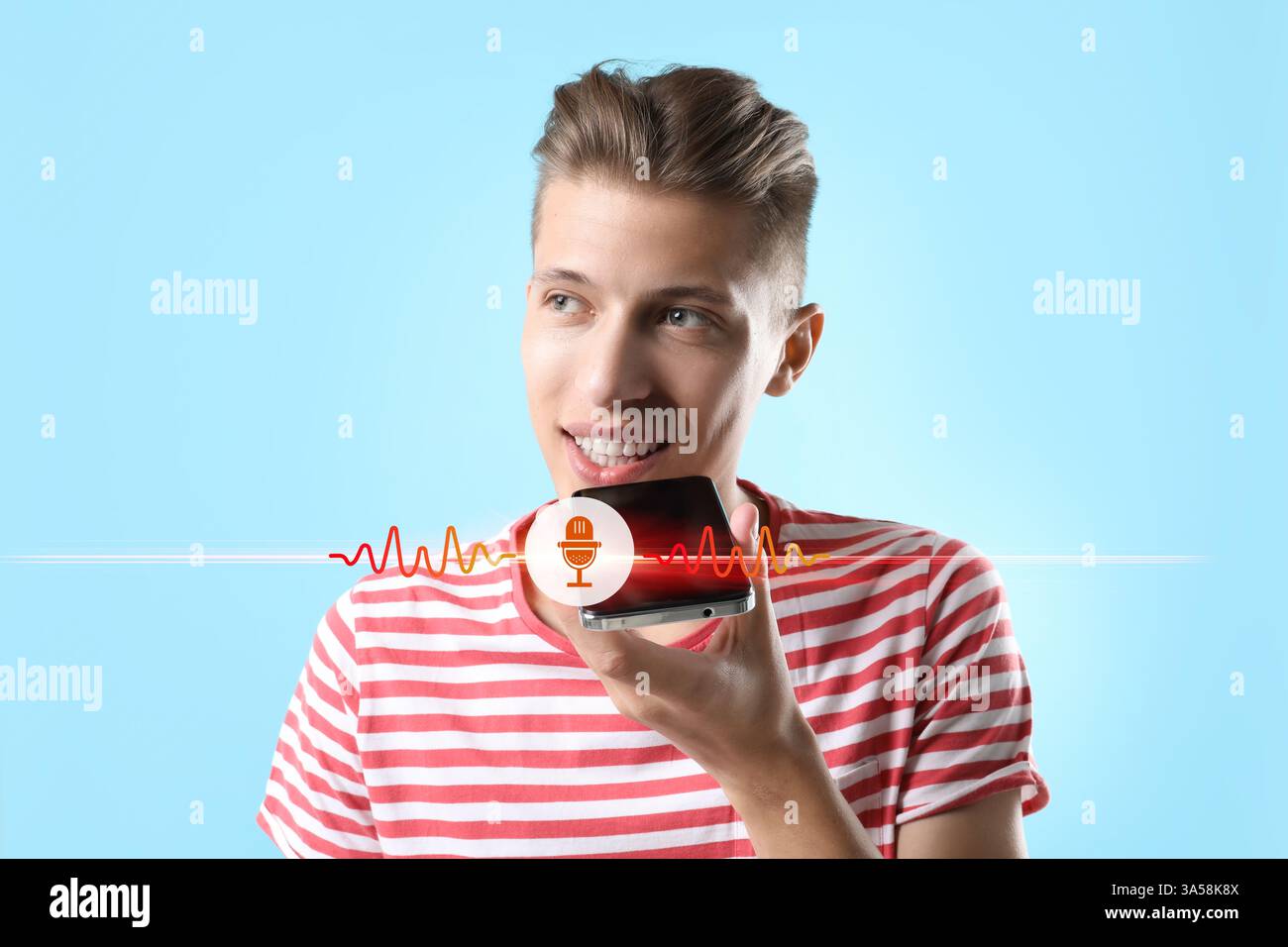 Young man recording voice message via smartphone on light blue ...