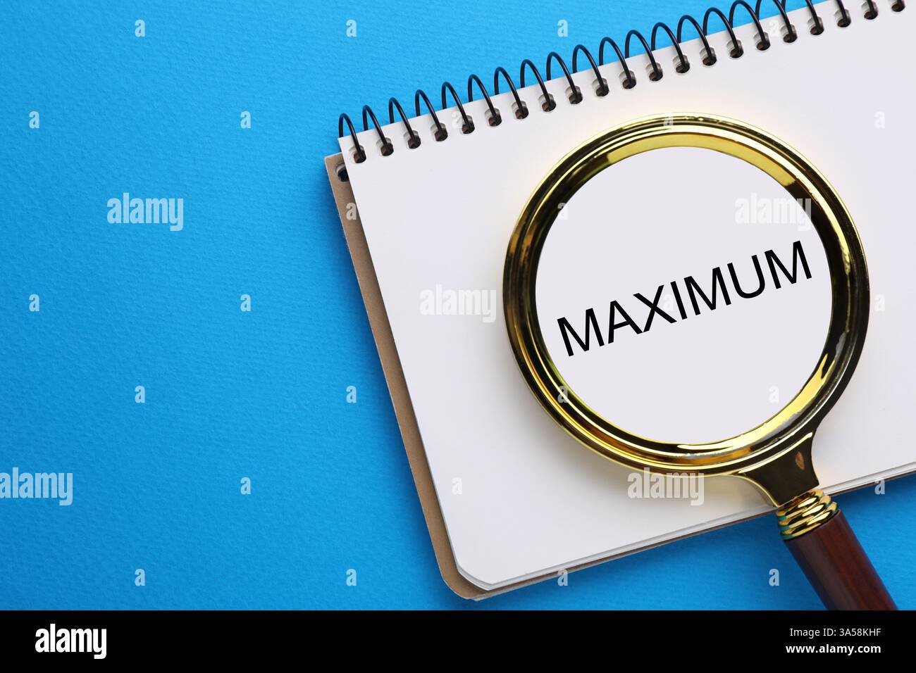 Word Maximum in notebook on blue background, view through magnifying ...