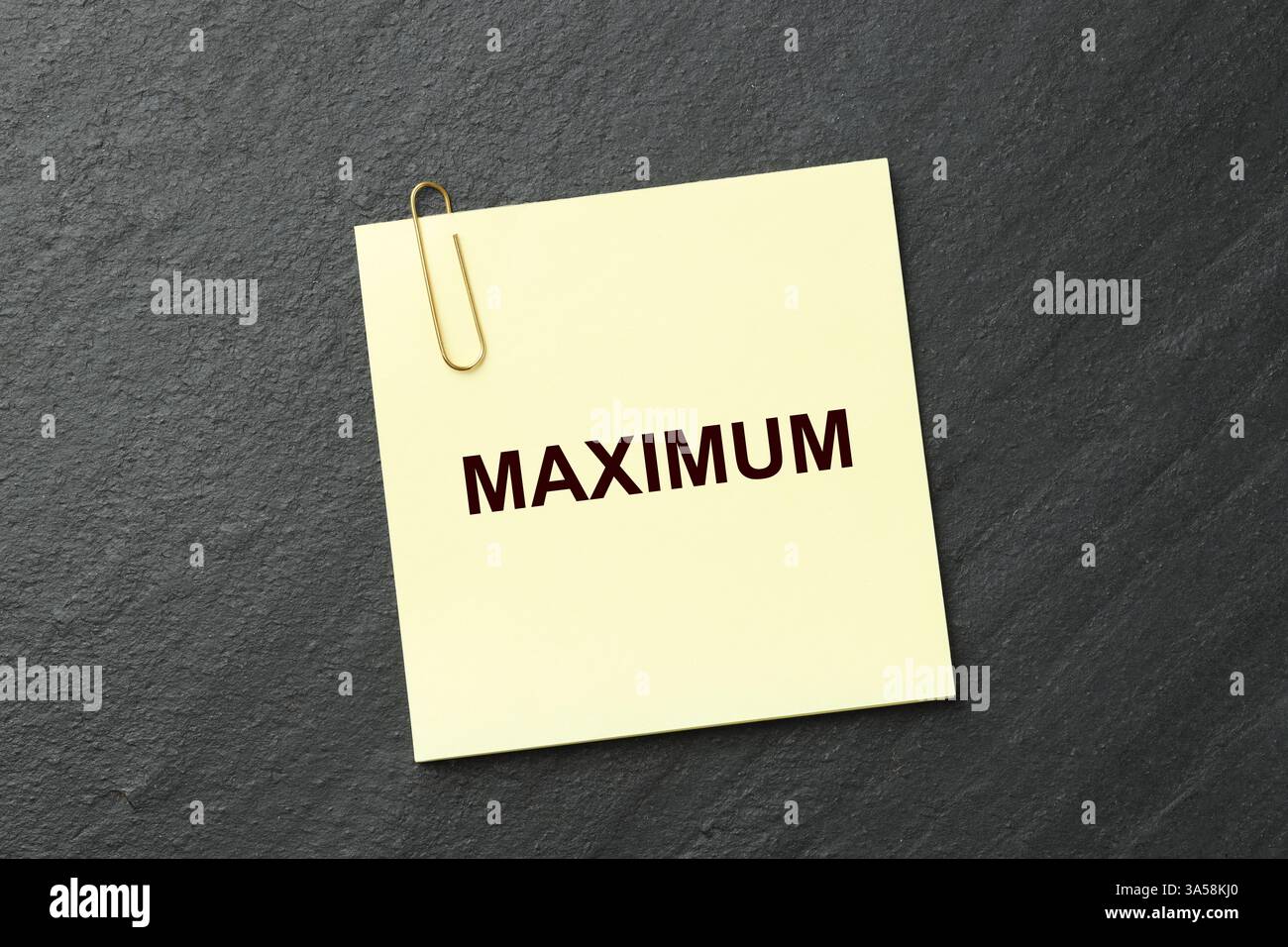 Note with word Maximum and paper clip on black table, top view Stock ...