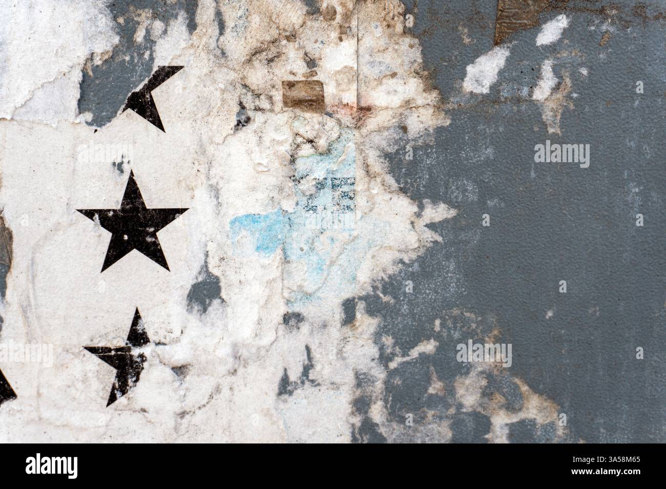A weathered wall displays peeling paint with a faded star pattern. The ...
