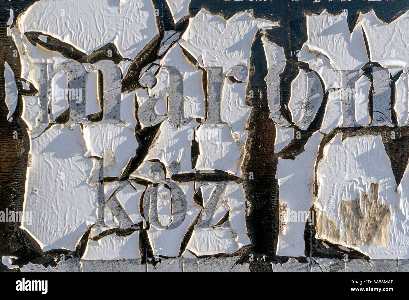 Cracked paint on a surface reveals faded lettering, showcasing a blend ...