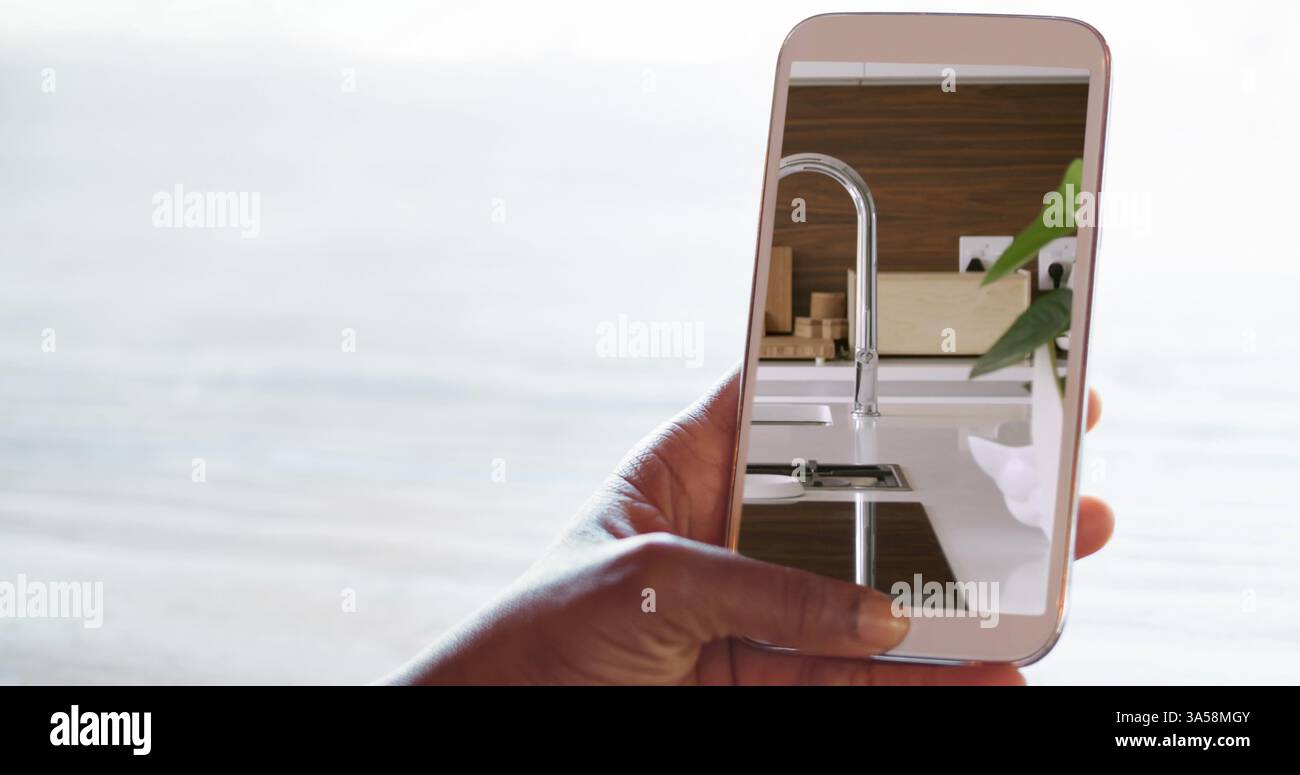 Holding smartphone, hand displaying modern kitchen faucet with digital ...