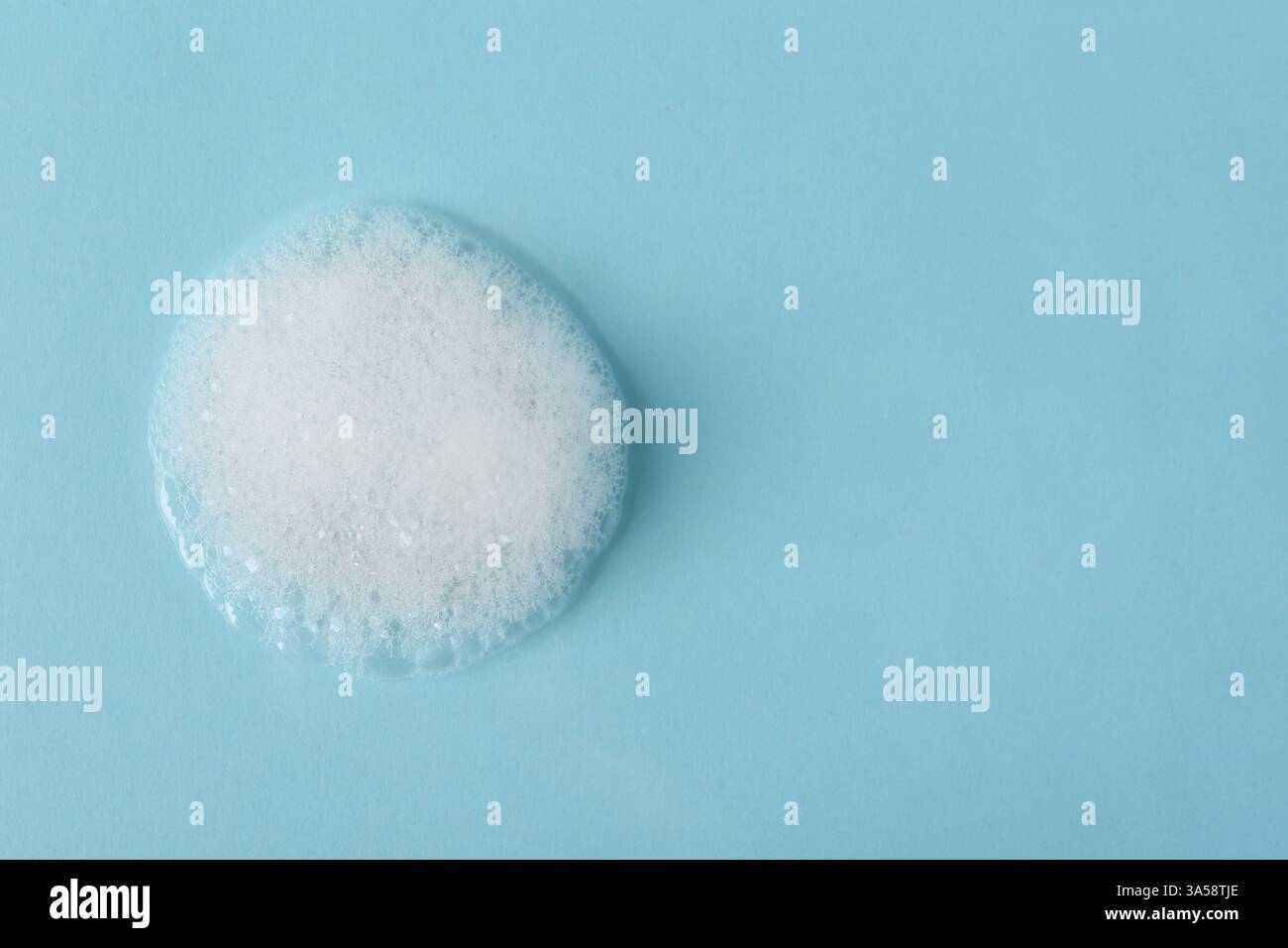 Sample of fluffy foam on light blue background, top view. Space for ...